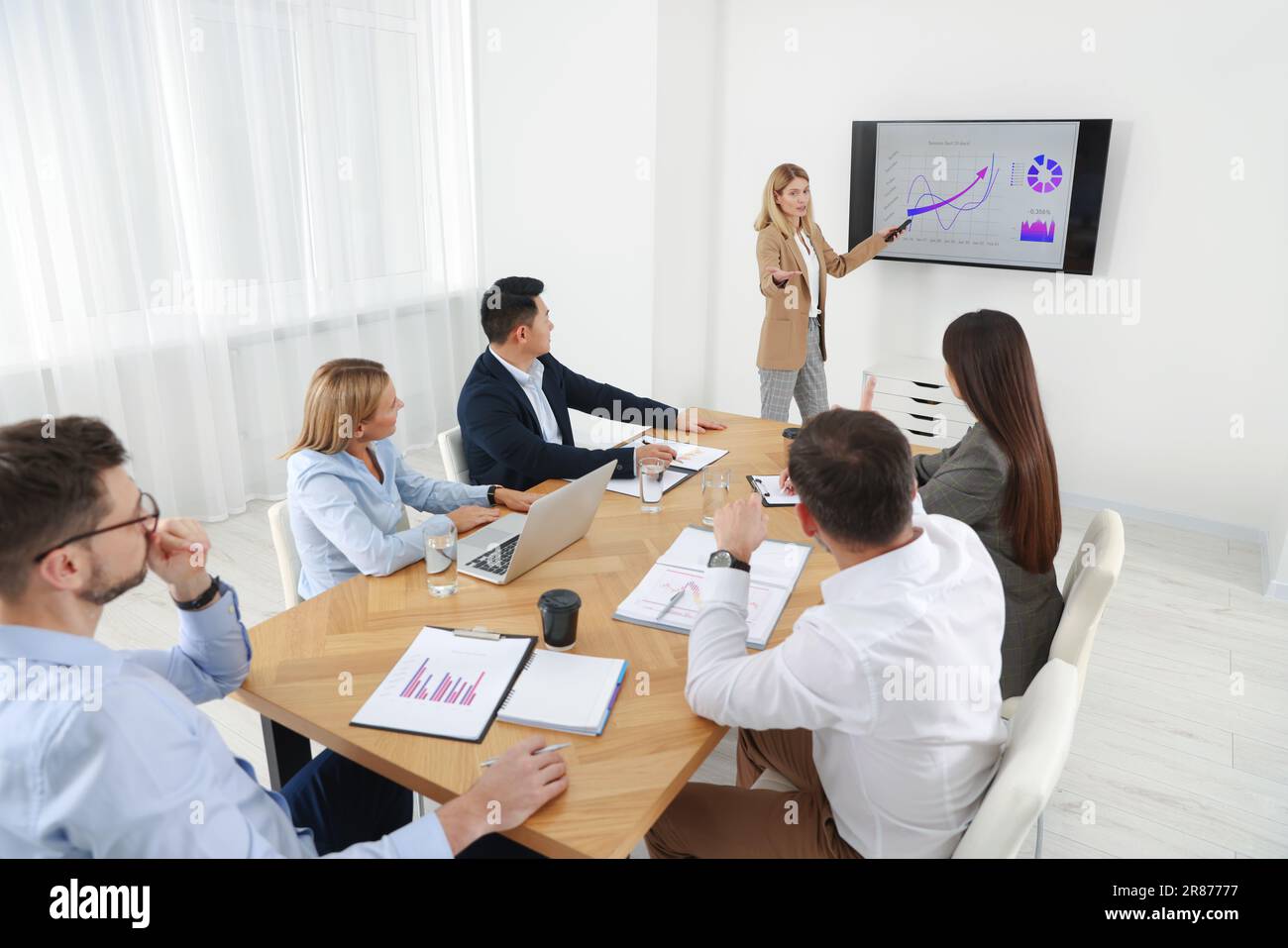 Businesswoman showing charts on tv screen in office Stock Photo - Alamy