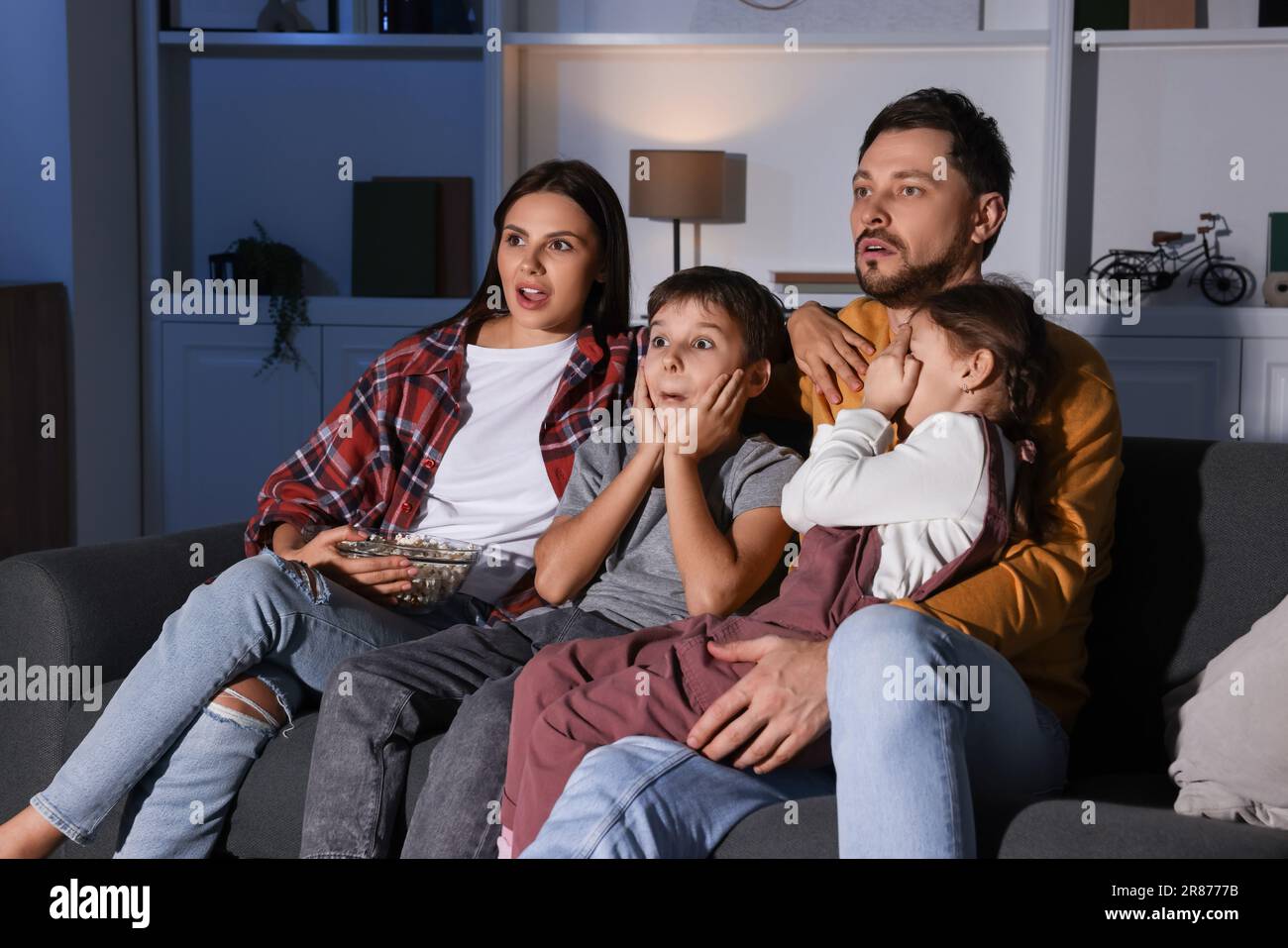 Emotional family watching TV at home in evening Stock Photo - Alamy
