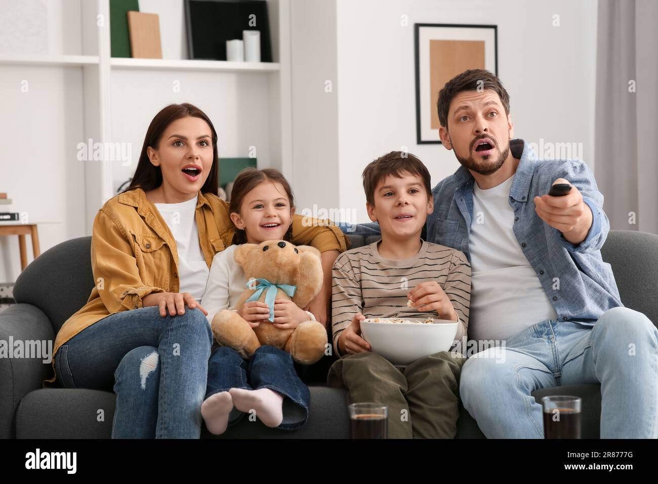 Emotional family watching TV at home. Father changing channels with ...