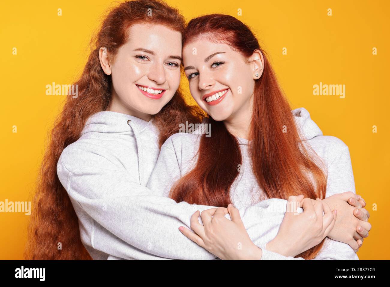 Portrait of beautiful young redhead sisters on orange background Stock ...