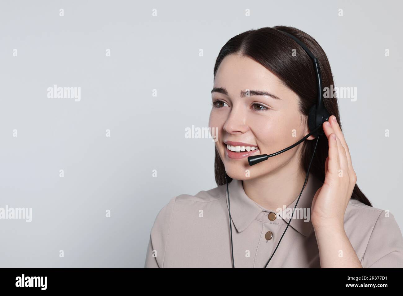 Hotline operator with modern headset on light grey background, space ...