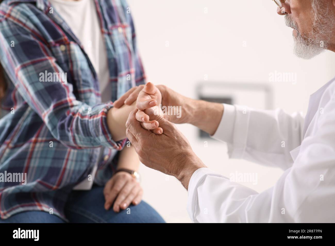 Orthopedist examining patient with injured hand in clinic, closeup ...