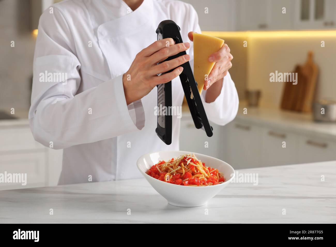 Professional chef grating cheese into delicious dish at white marble ...