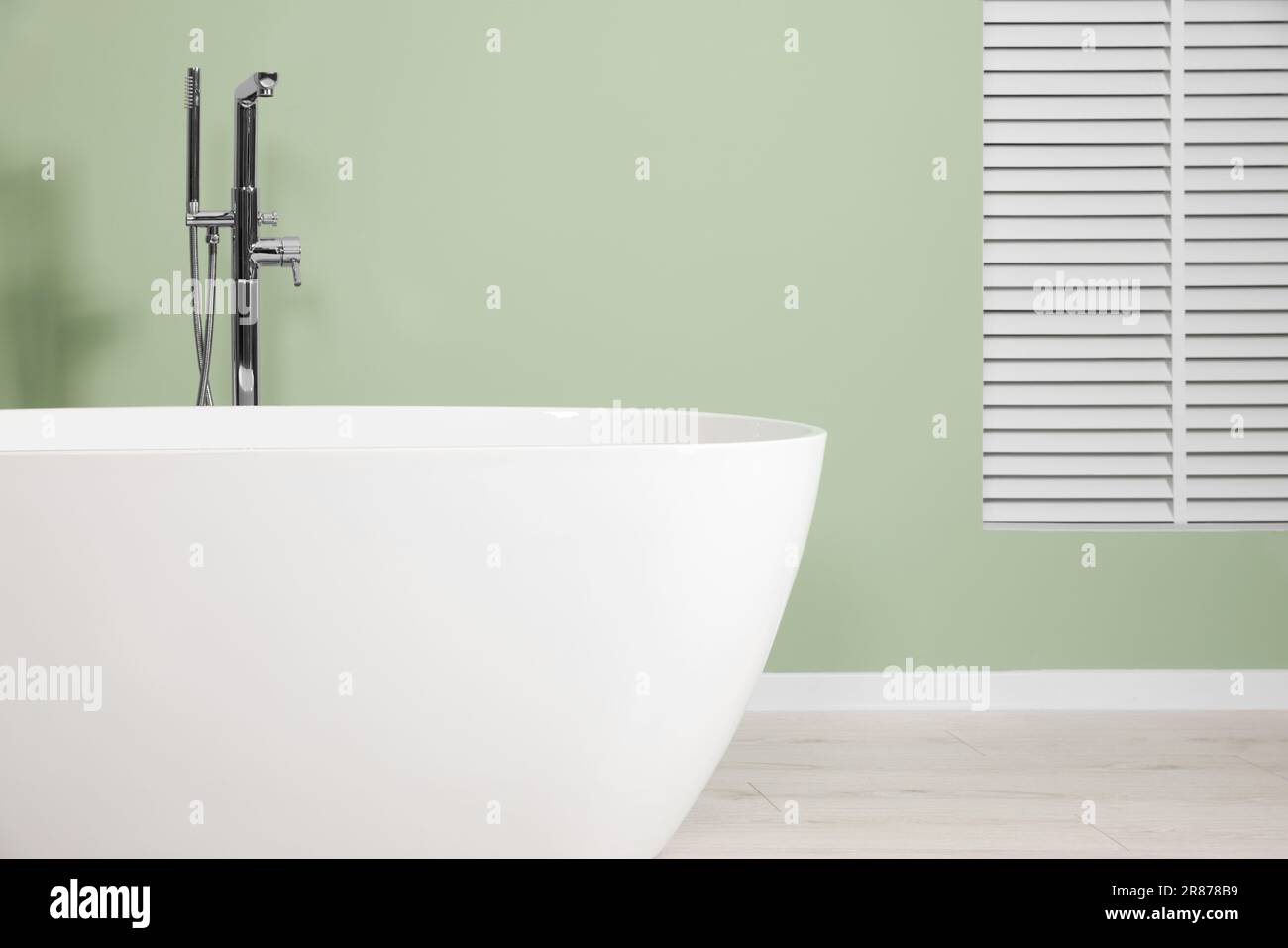 Modern ceramic tub near light green wall in bathroom. Interior design ...