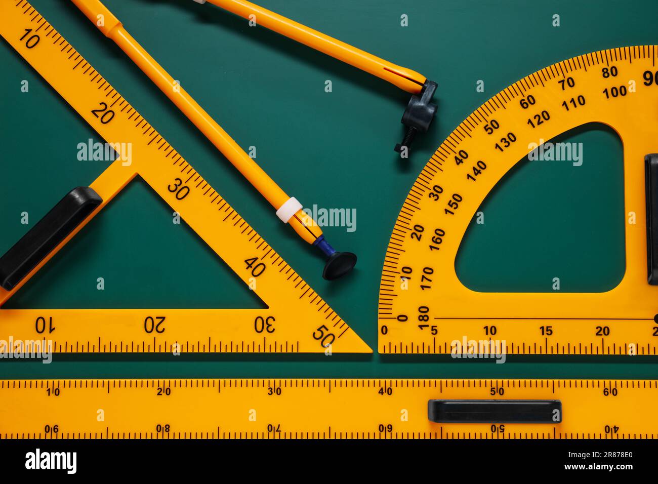 Protractor, triangle, ruler and compass on green chalkboard, flat lay ...