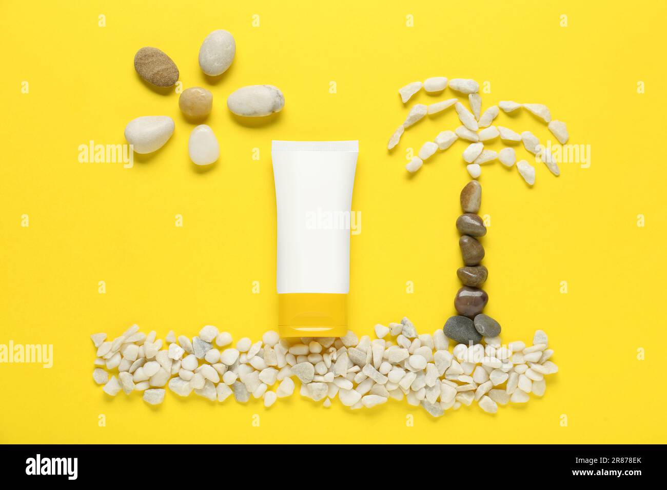 Suntan cream, sun and palm made of marble pebbles on yellow background ...