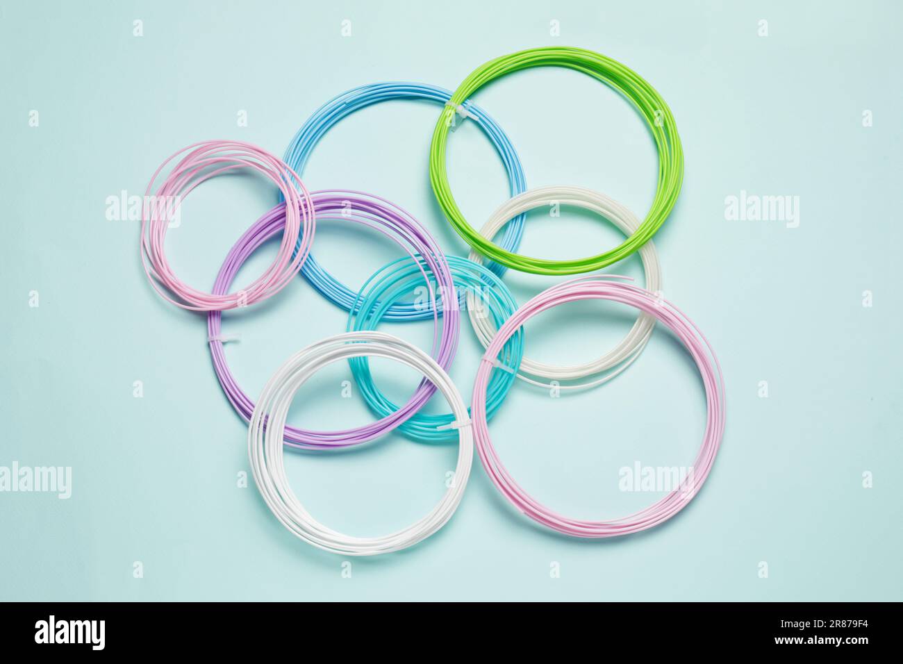 Colorful plastic filaments for 3D pen on light blue background, flat ...