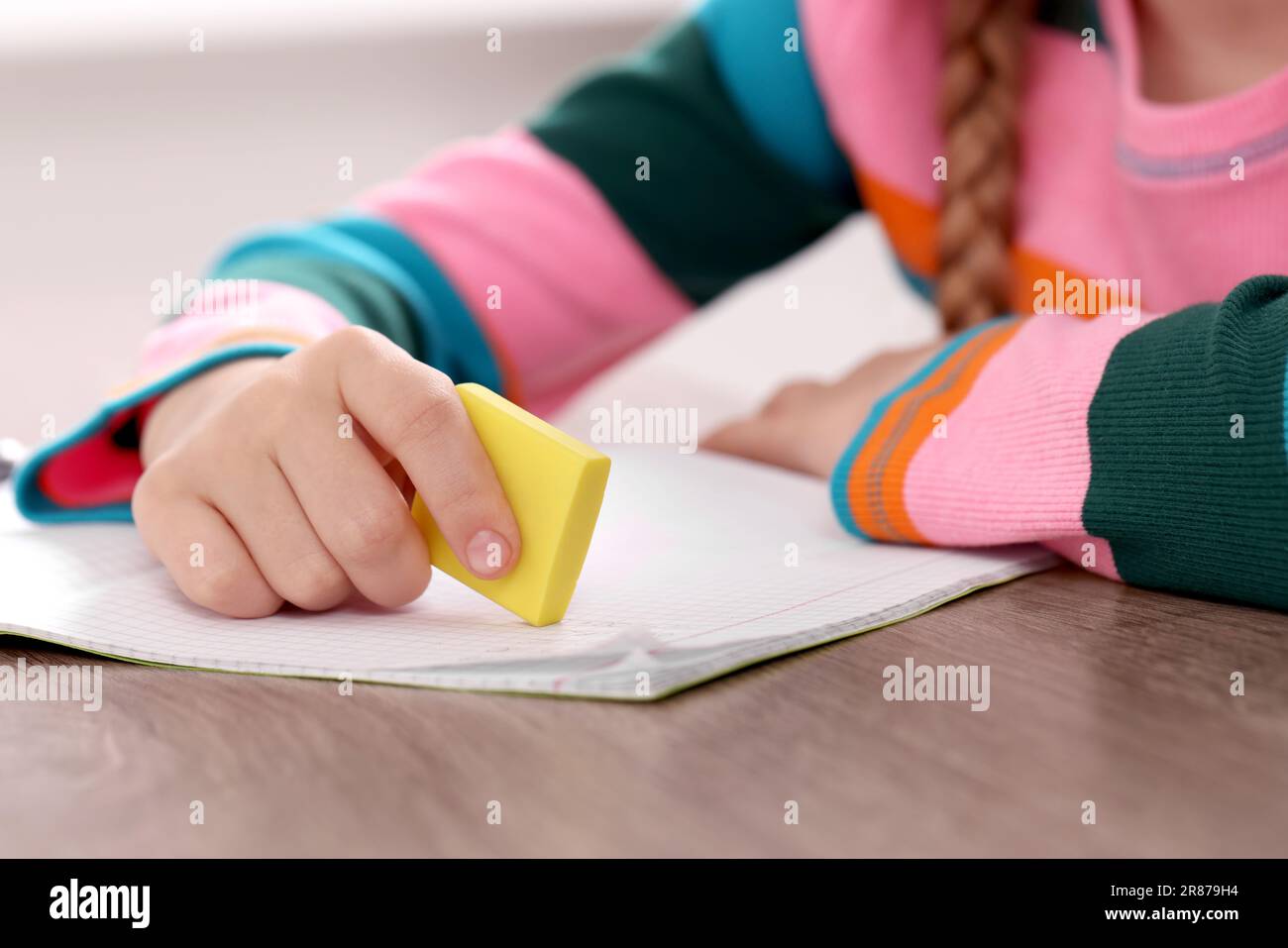 Girl erasing mistake in her homework at wooden table, closeup Stock ...