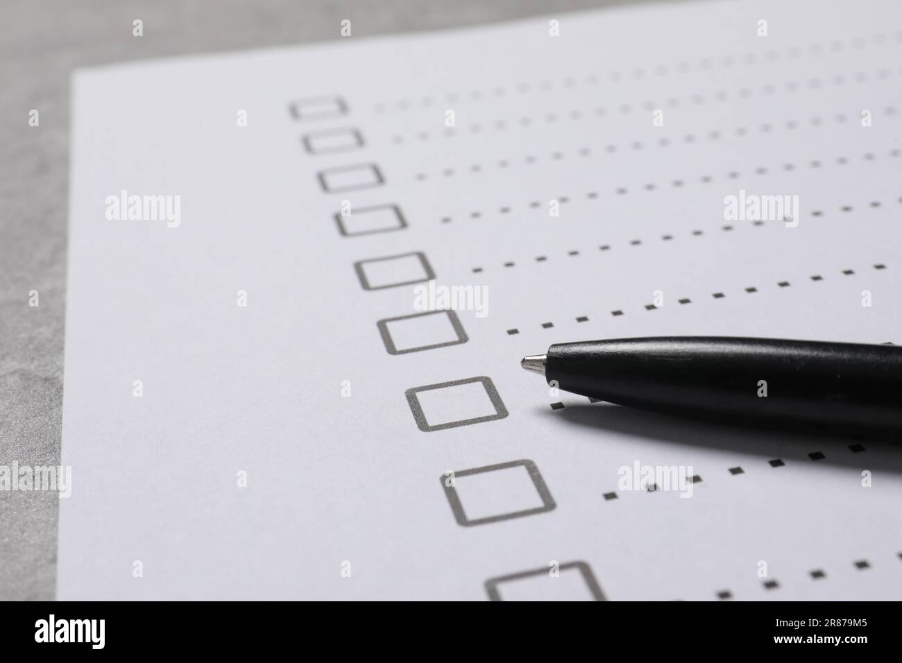 Paper sheet with checkboxes and pen on light grey table, closeup ...