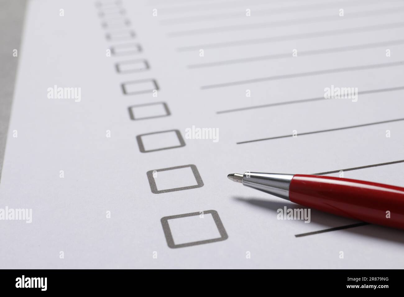 Paper sheet with checkboxes and pen on light grey table, closeup ...