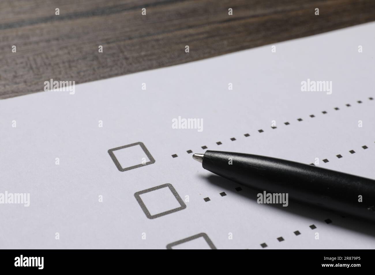 Paper sheet with checkboxes and pen on wooden table, closeup. Checklist ...