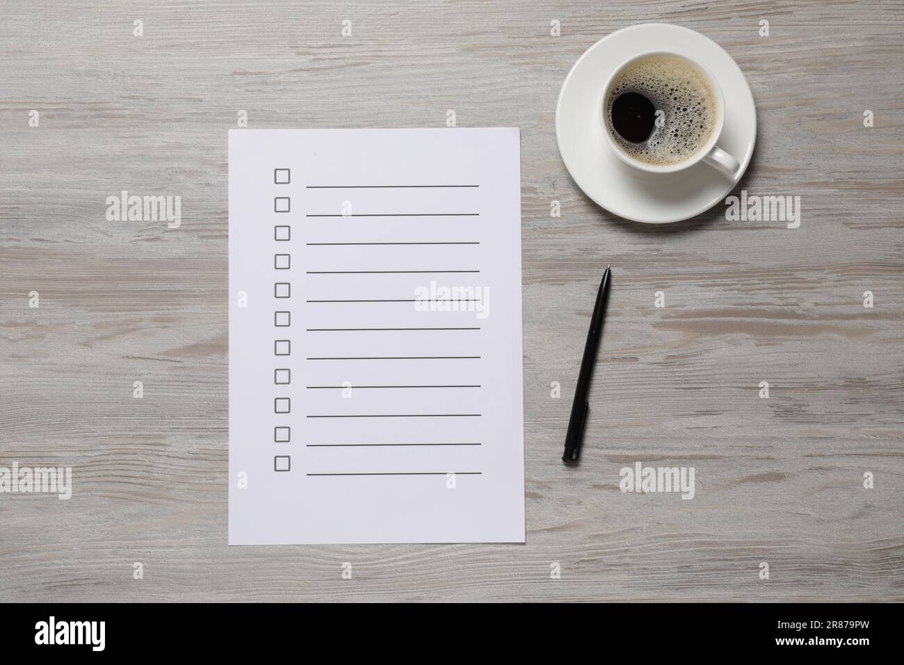 Paper sheet with checkboxes, cup of coffee and pen on white wooden ...