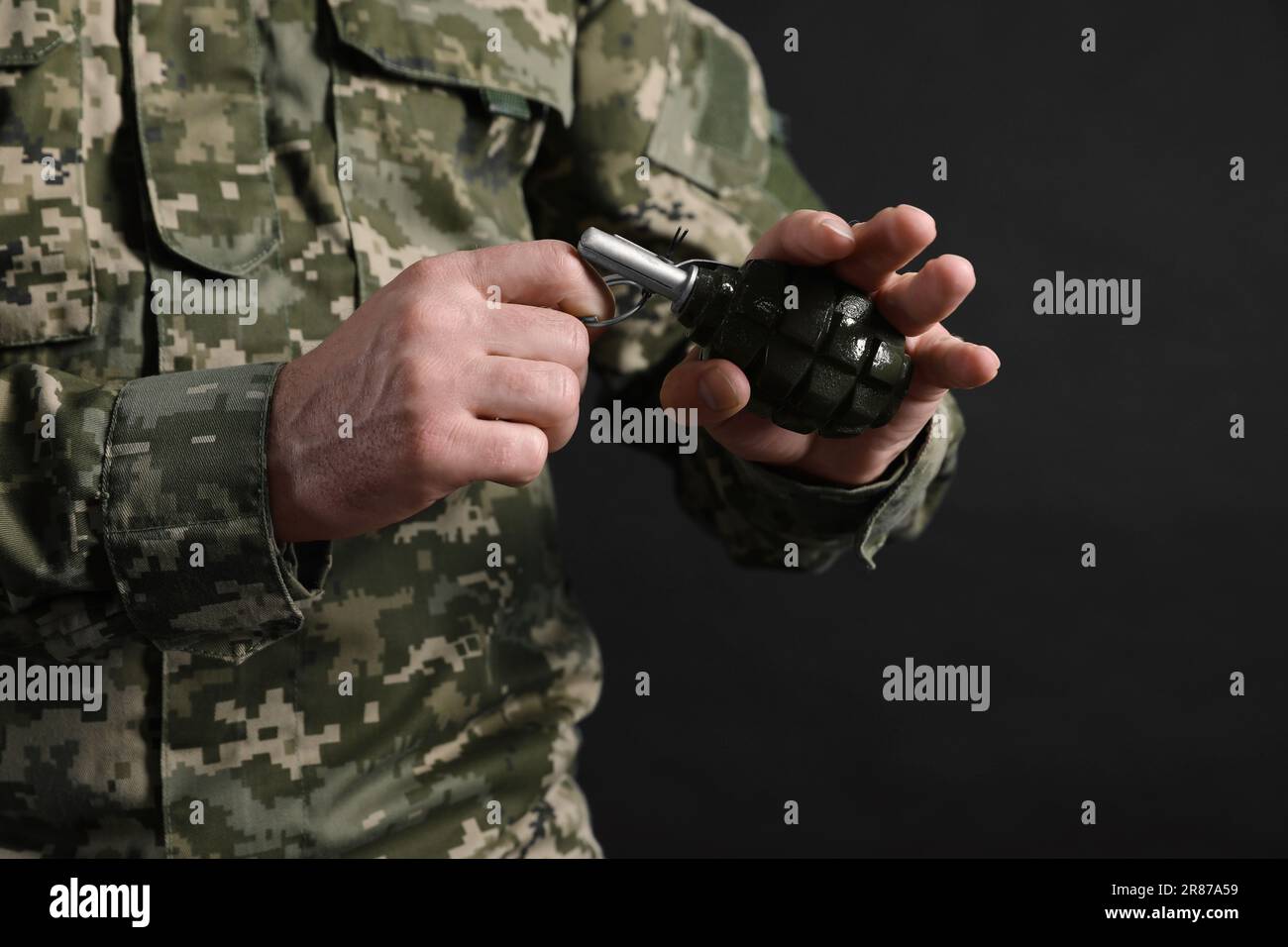 Soldier pulling safety pin out of hand grenade on black background ...