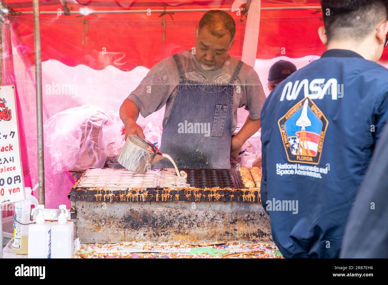 Japanese food stall and chef cooking and serving octopus balls Takoyaki ...