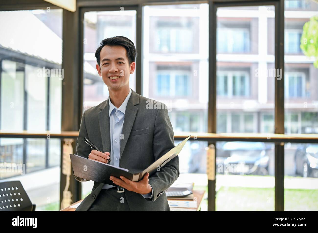 A smiling and smart millennial Asian businessman or male banker in a ...