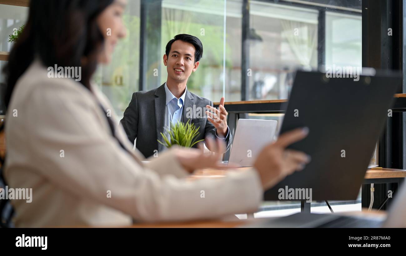 A friendly and smart millennial Asian businessman is talking and ...