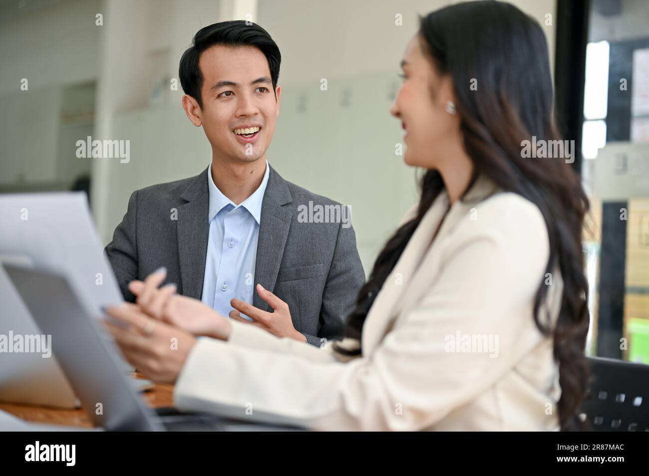 A happy and handsome millennial Asian businessman is sharing his ideas ...