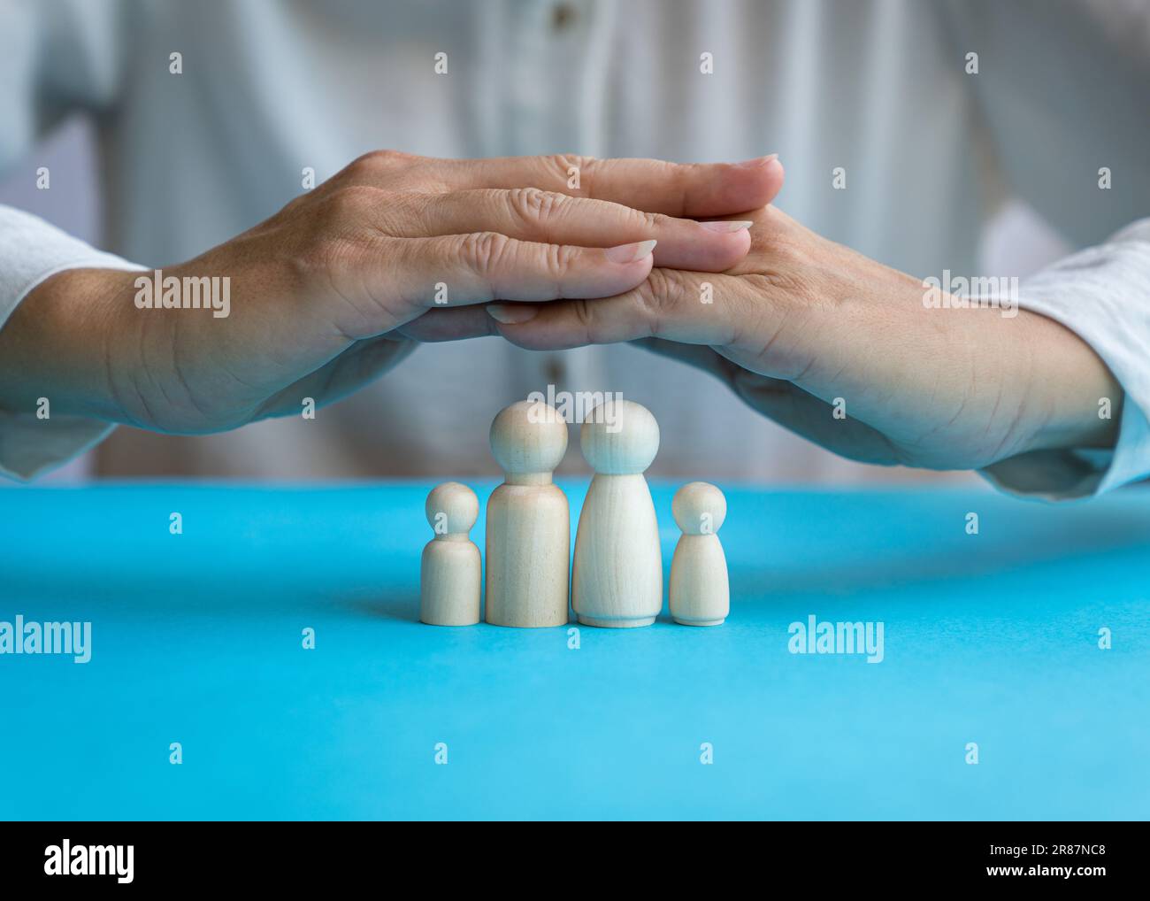 Woman's hands cover over wooden doll family with father, mother ...
