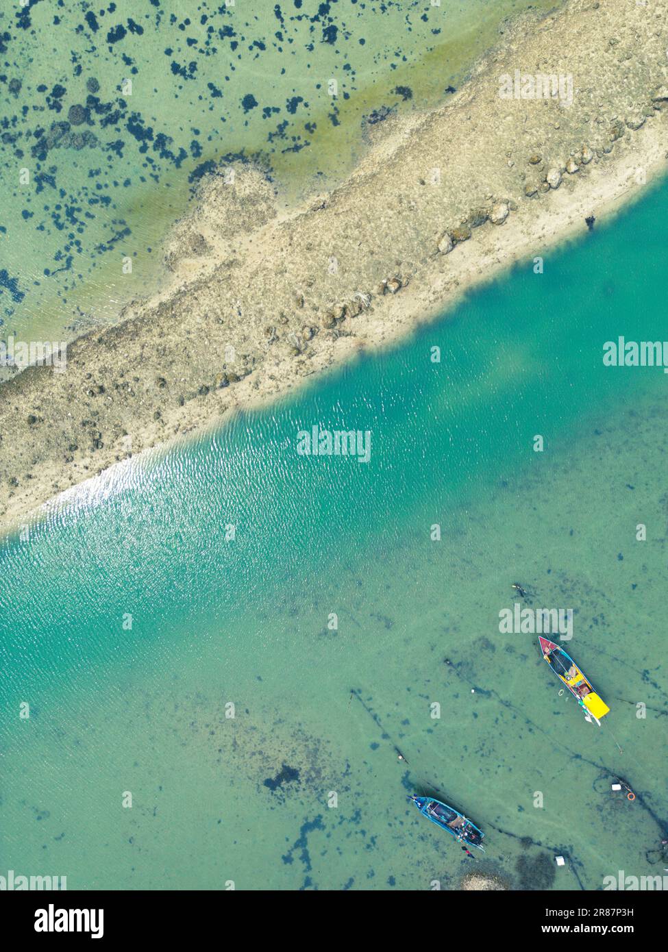 An aerial view of a fleet of colorful boats on a coastal shoreline ...