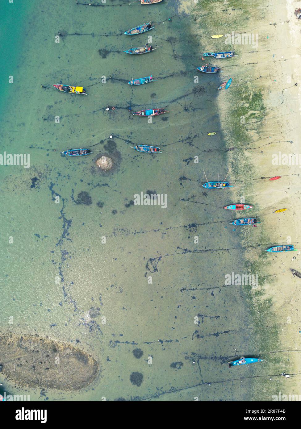 An aerial view of a fleet of colorful boats on a coastal shoreline ...