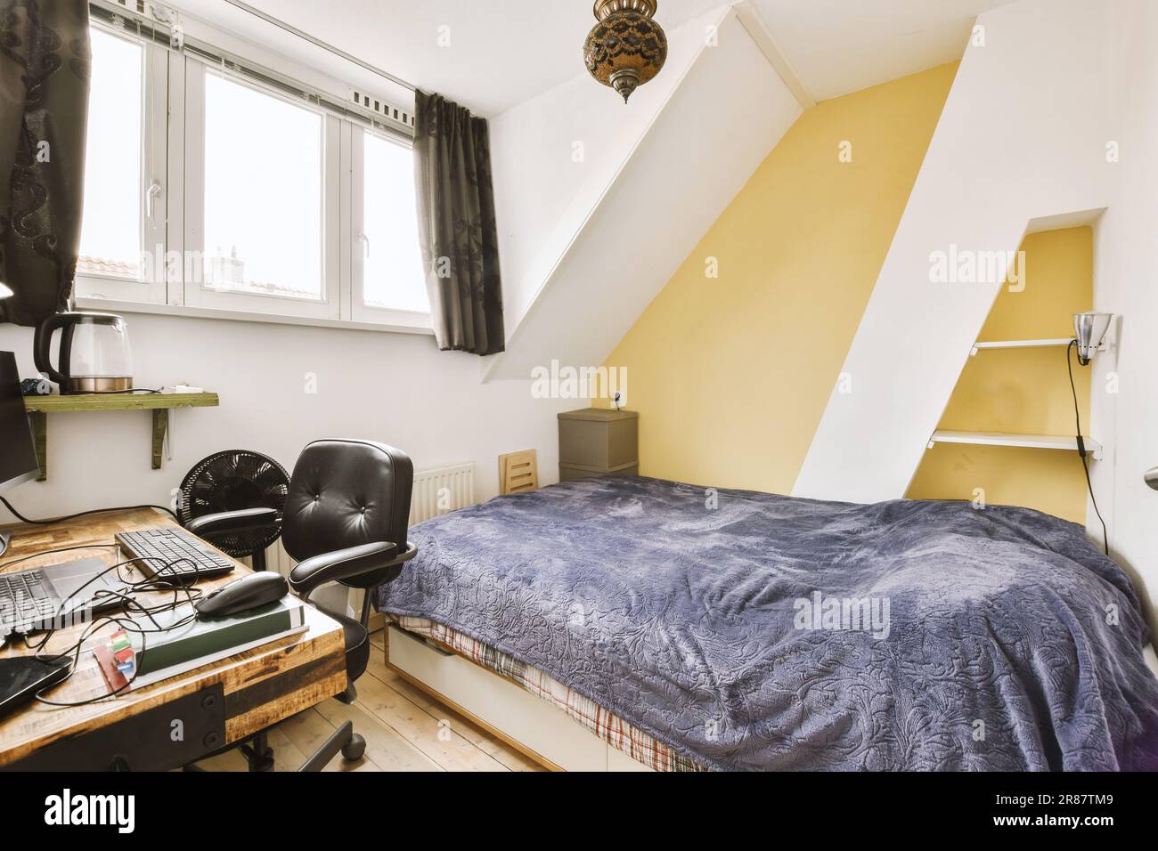 a bedroom with a bed, desk and computer monitor on the table in front ...