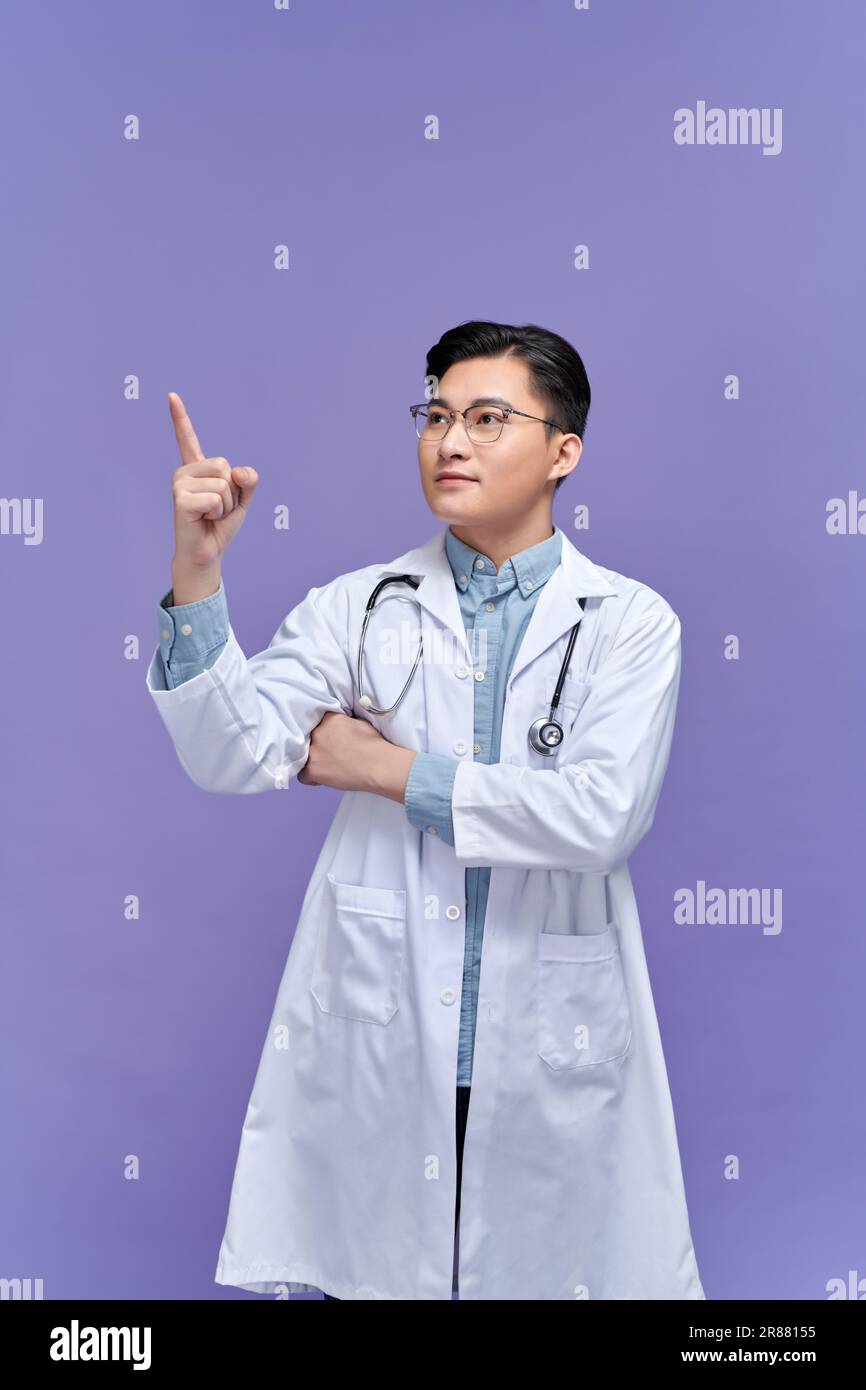 Young handsome doctor man smiling cheerfully pointing with forefinger ...