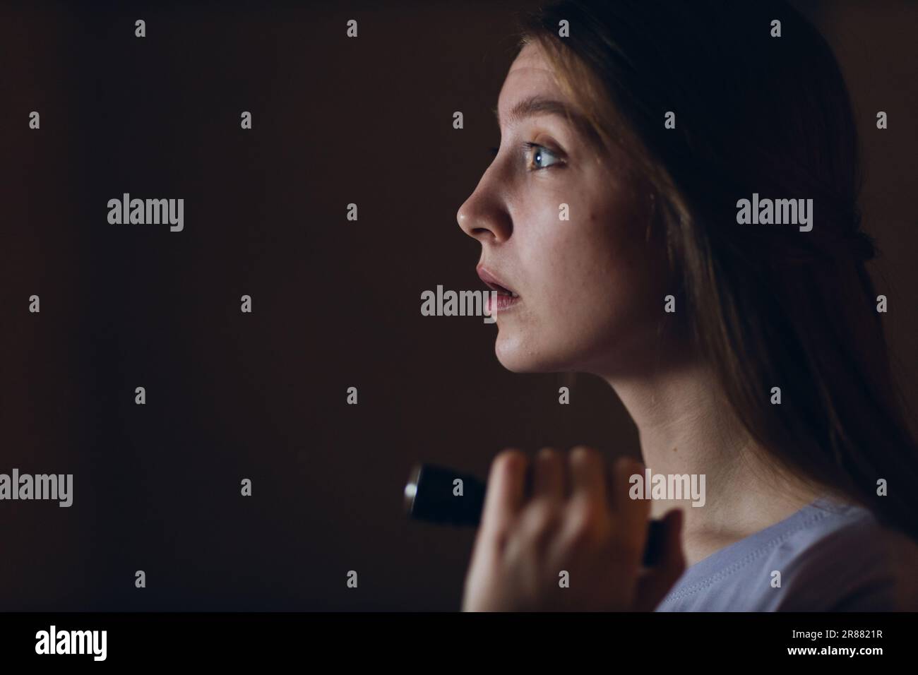 Woman scared holding hand flashlight in darkness and afraid of violence ...