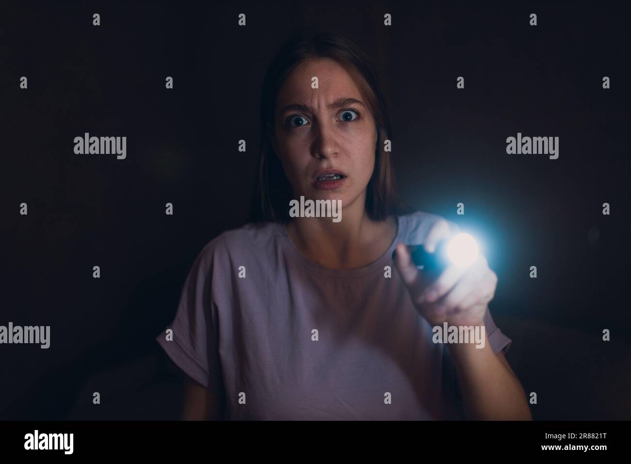 Woman scared holding hand flashlight in darkness and afraid of violence ...