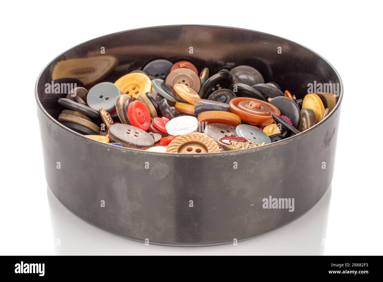 Many buttons in a black round, plastic container, macro, isolated on ...