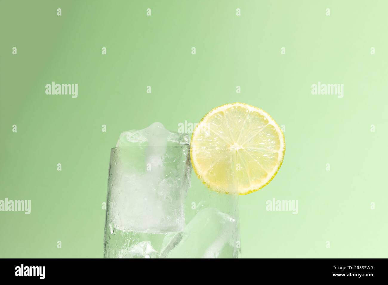 Cold glass full of ice with a lime, ready to serve light green with ...