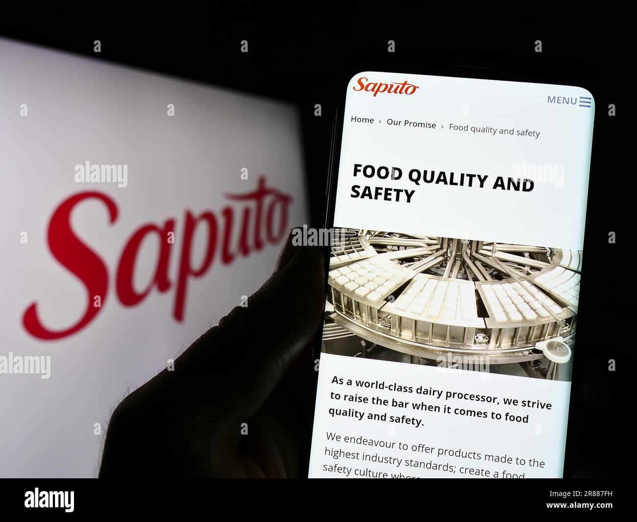 Person holding mobile phone with webpage of Canadian dairy company ...