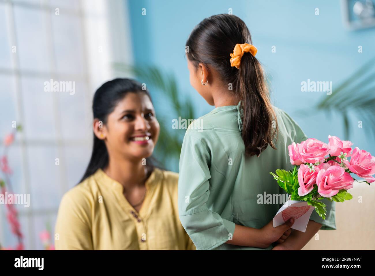 Focus on flowers, Shoulder shot of indian girl kid giving flowers with ...
