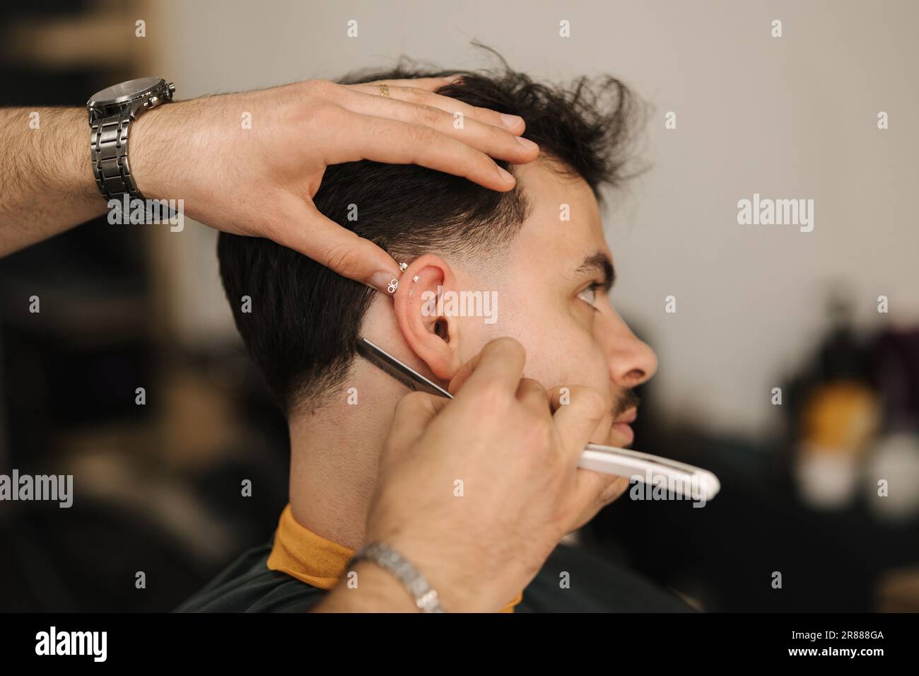 Side view of barber using sharp blade for shaving. Handsome customer ...