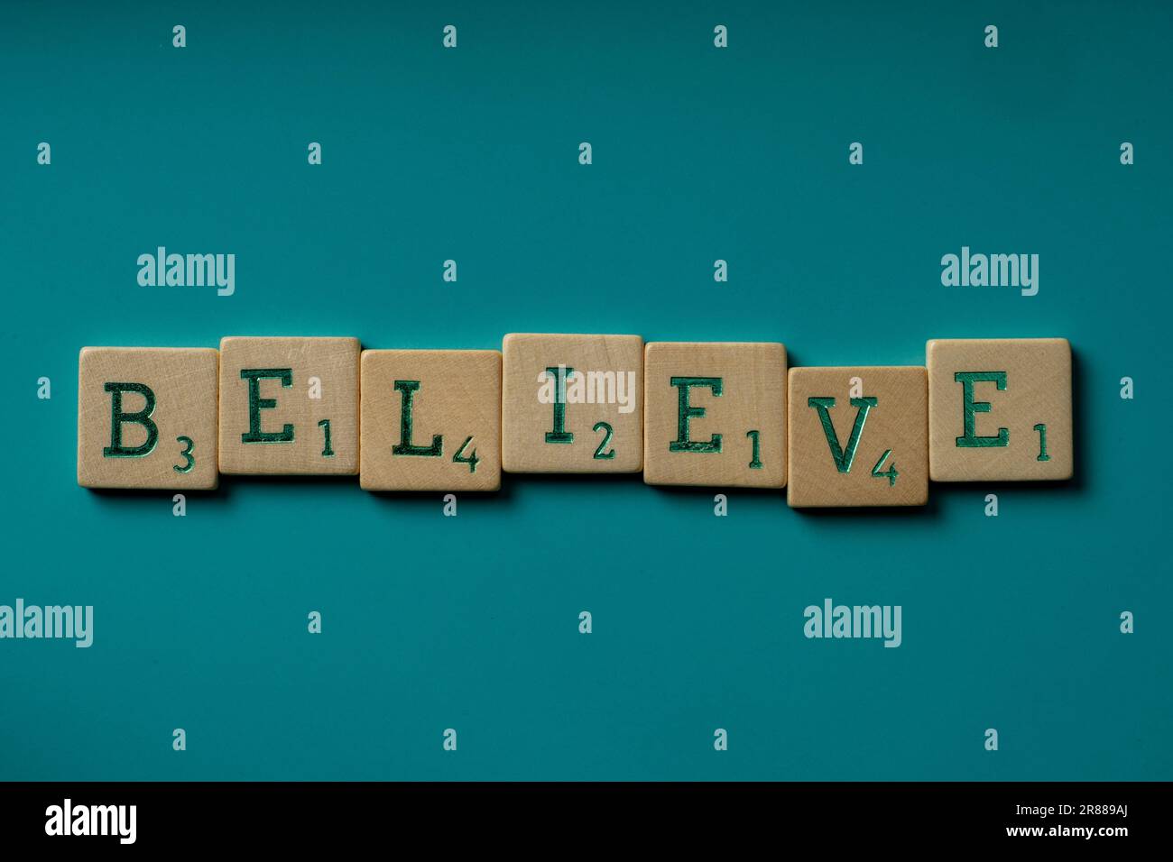 The wooden letters spelling the word believe on a blue background Stock ...