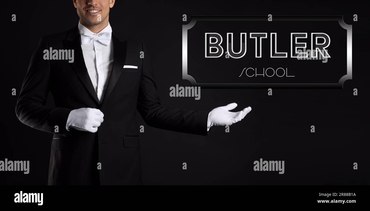 Man in elegant suit pointing at sign Butler School on black background ...
