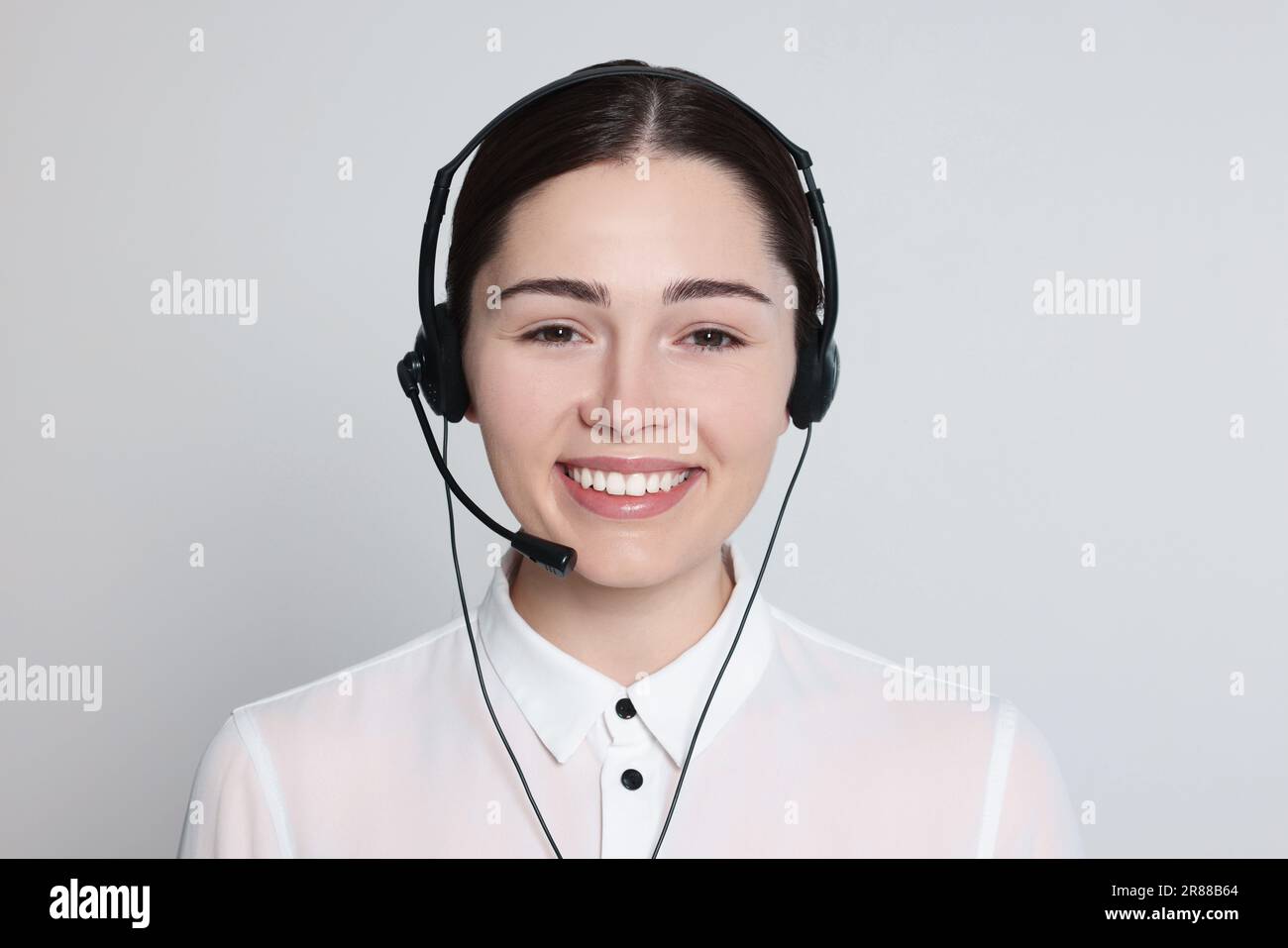 Hotline operator with modern headset on light grey background. Customer ...