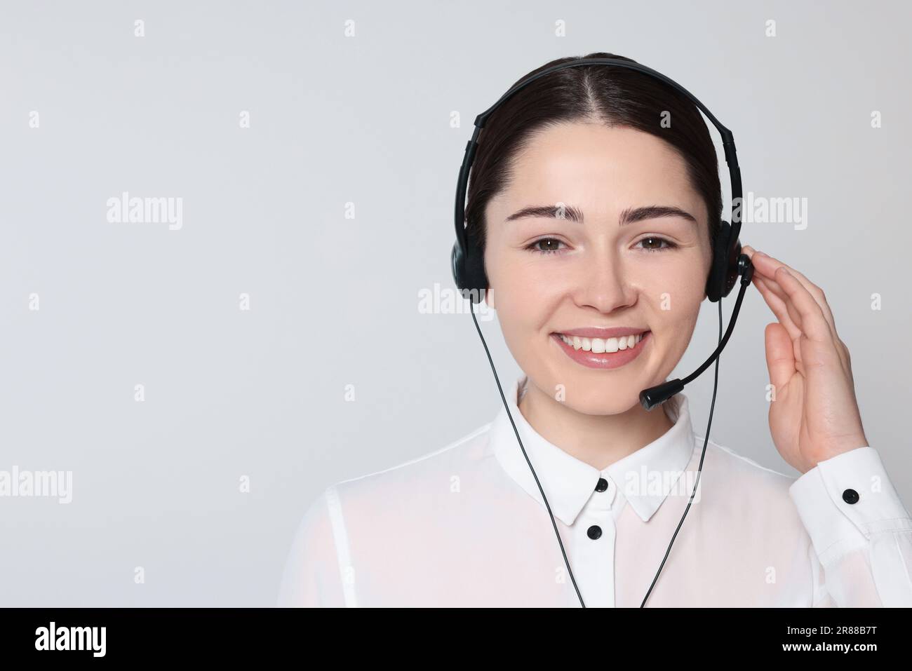 Hotline operator with modern headset on light grey background, space ...