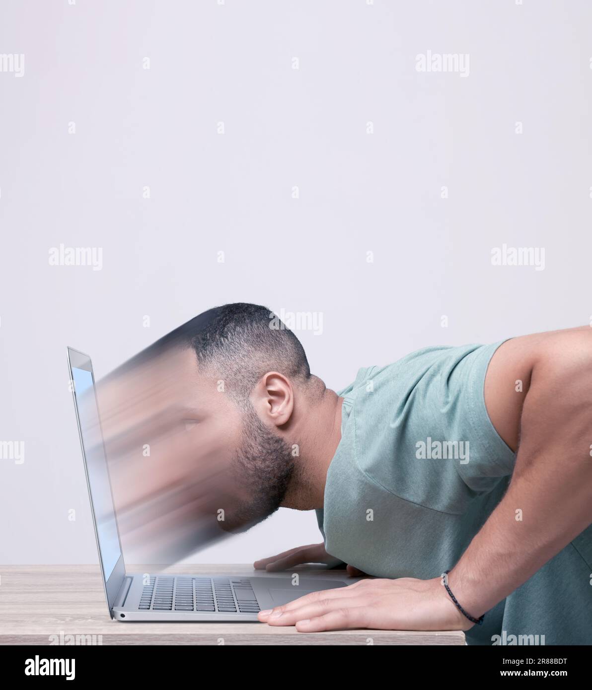 Internet addiction. Young man dissolving in laptop at table Stock Photo ...