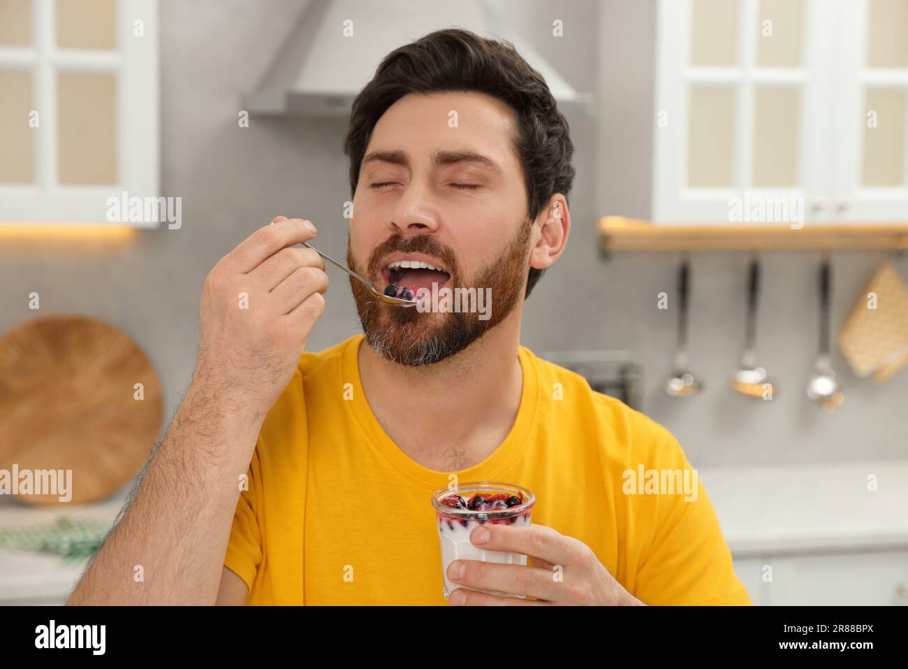 Man eating yogurt in kitchen hi-res stock photography and images - Alamy