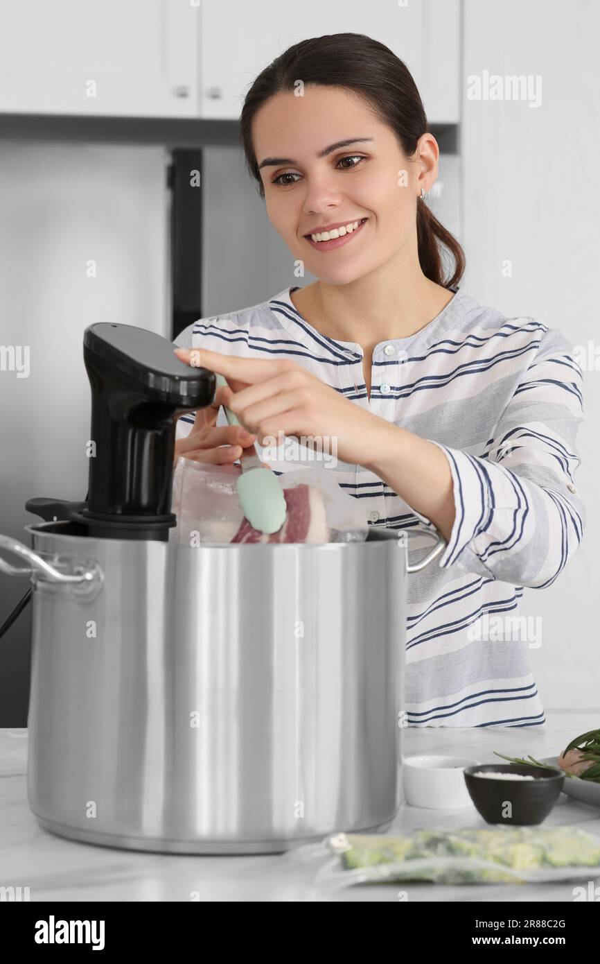 Woman putting vacuum packed meat into pot and using thermal immersion ...