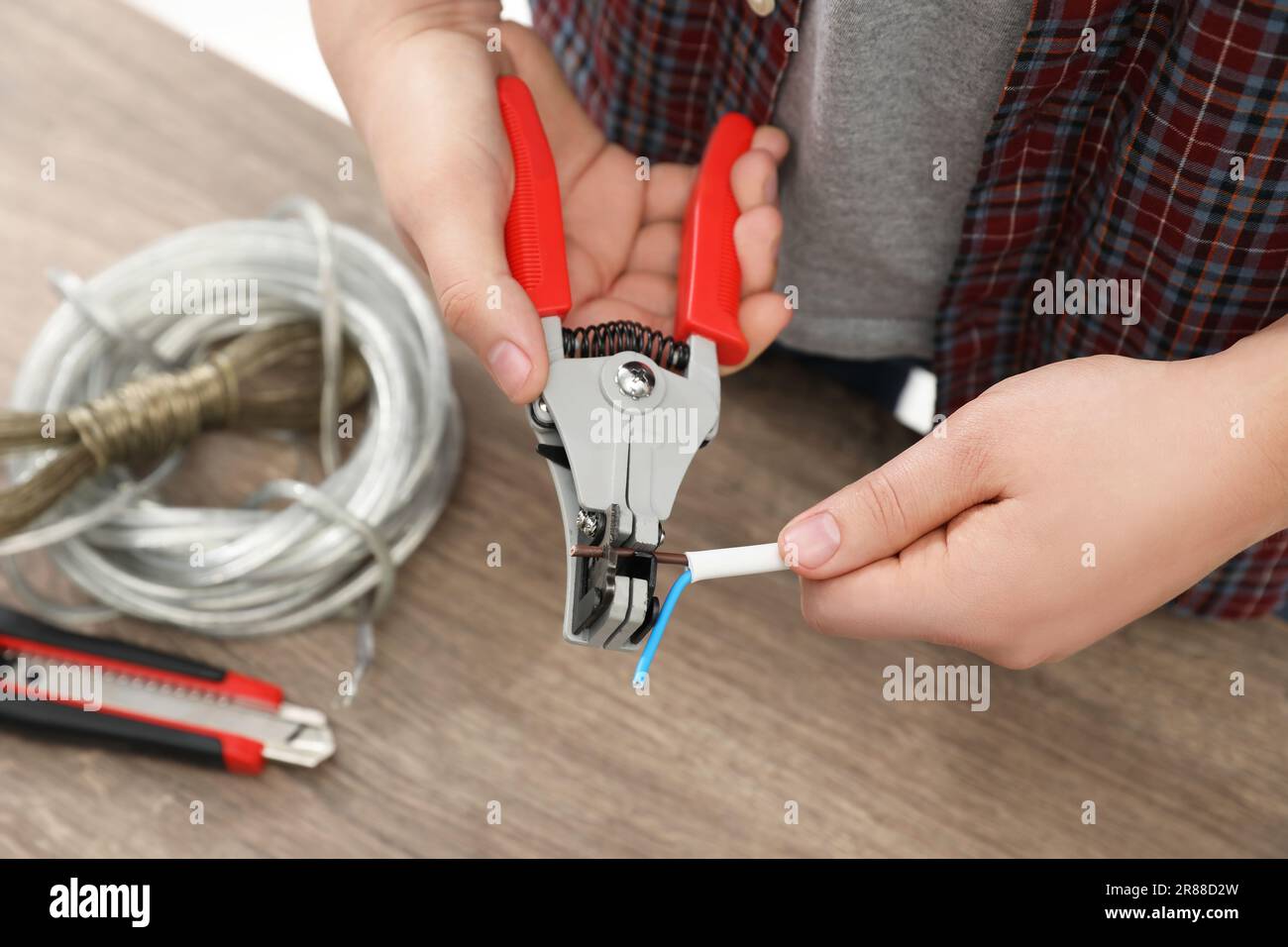 Professional electrician stripping wiring at wooden table, above view ...