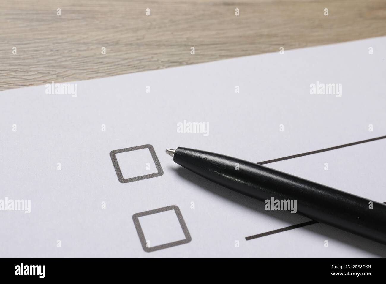 Paper sheet with checkboxes and pen on wooden table, closeup. Checklist ...