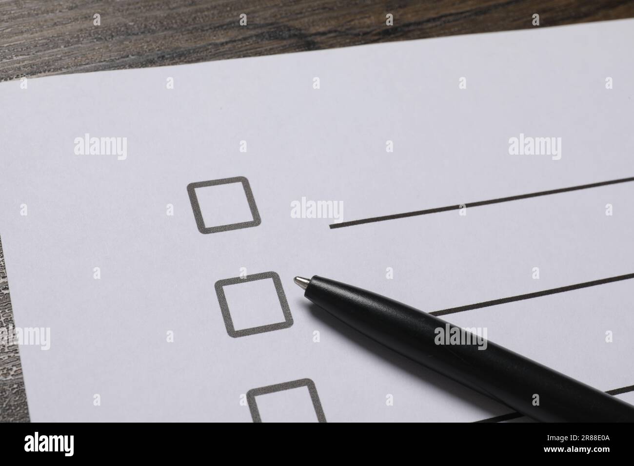 Paper sheet with checkboxes and pen on wooden table, closeup. Checklist ...