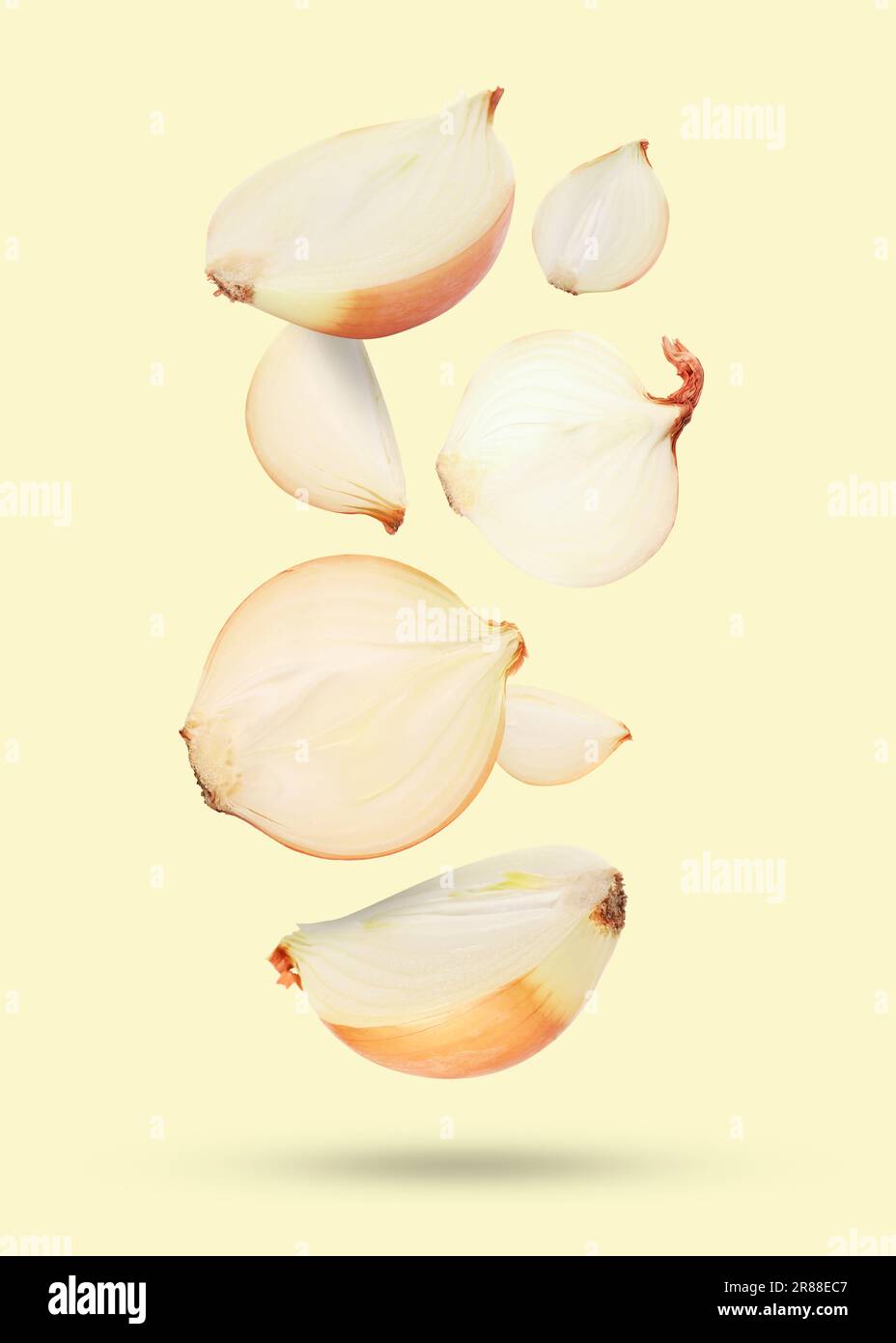 Cut fresh onions falling on beige background Stock Photo - Alamy