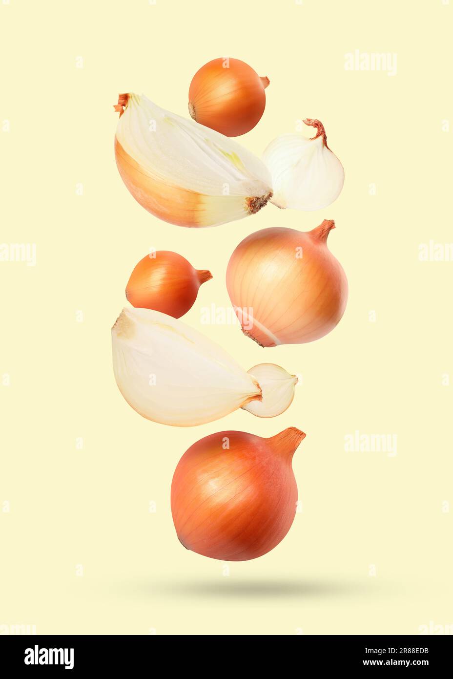 Cut and whole onions falling on beige background Stock Photo - Alamy