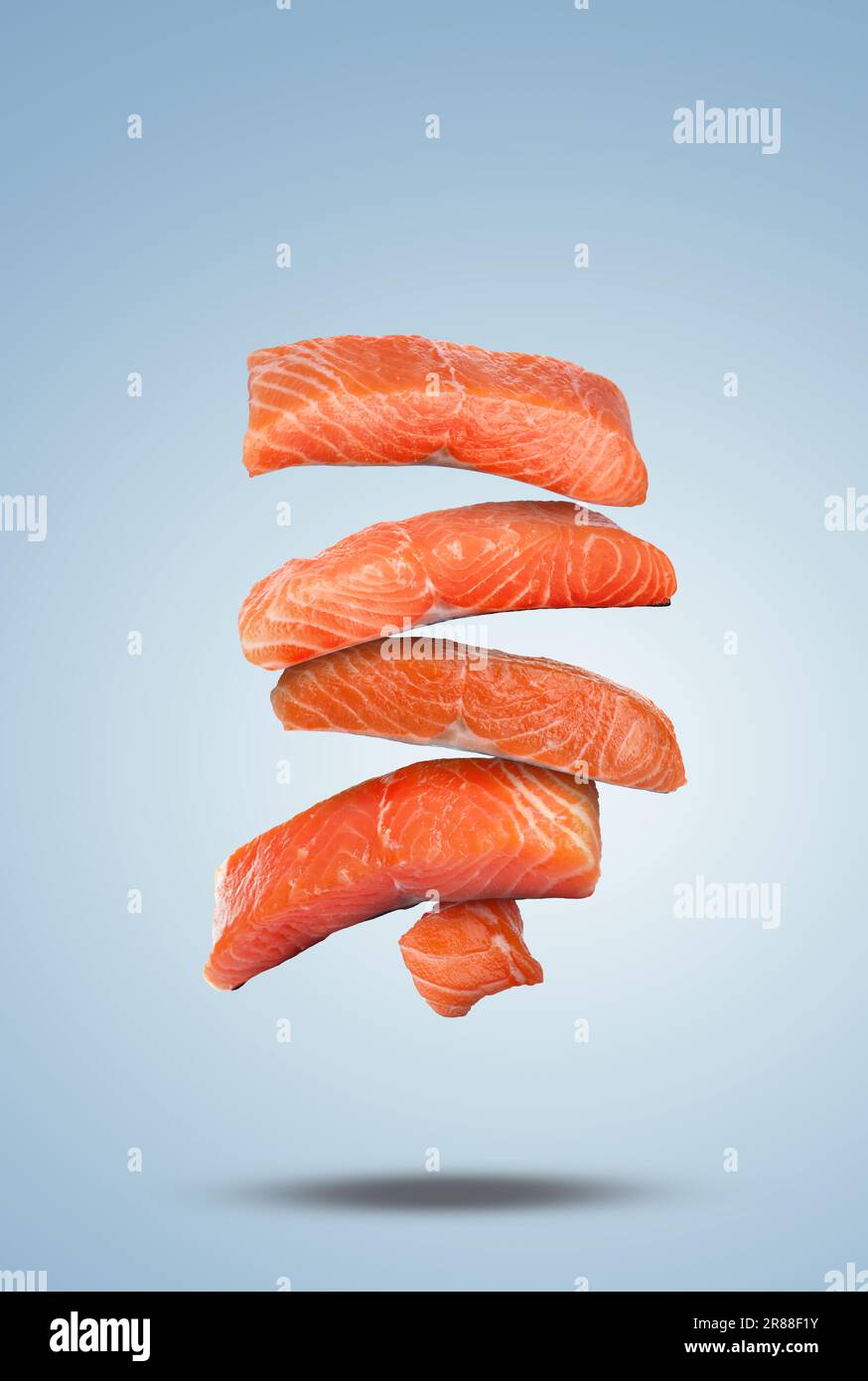 Cut fresh salmon falling on pale light blue gradient background Stock ...