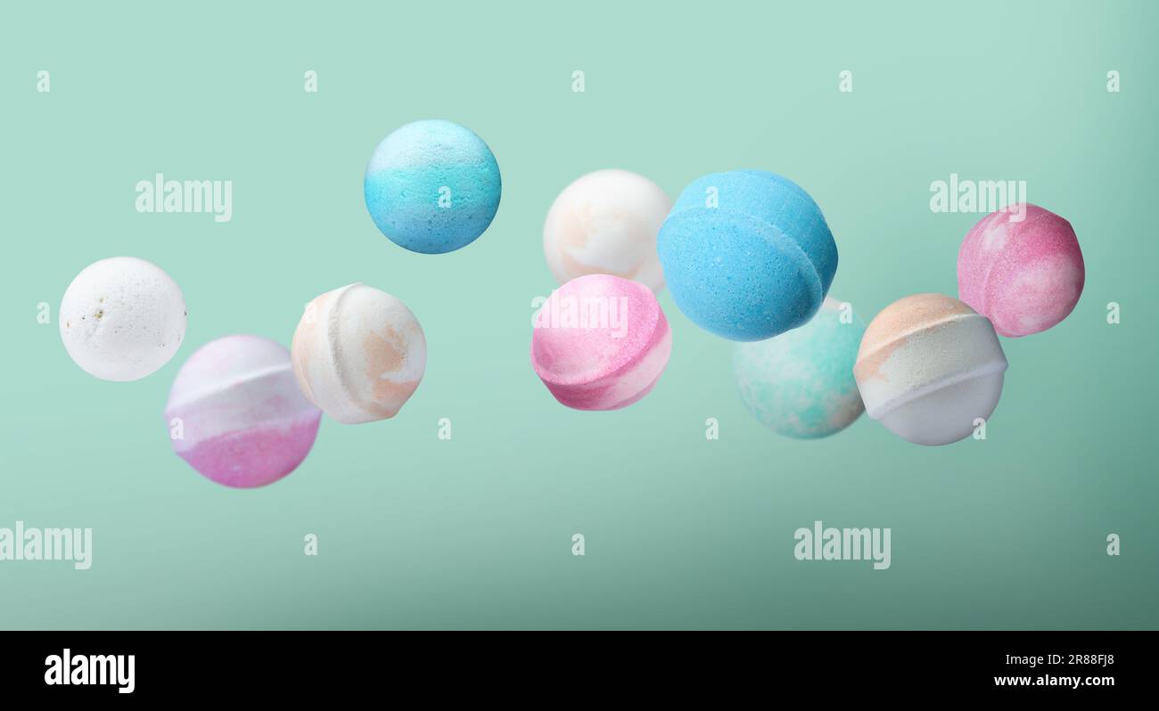 Many different bath bombs falling on pastel turquoise background ...