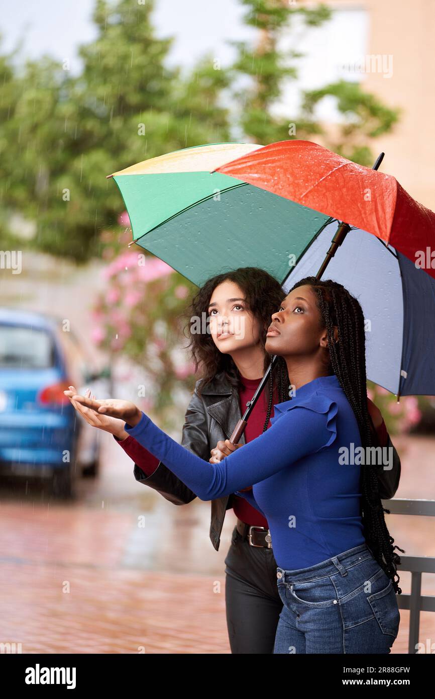 Two women checking weather while standing on the street under an ...