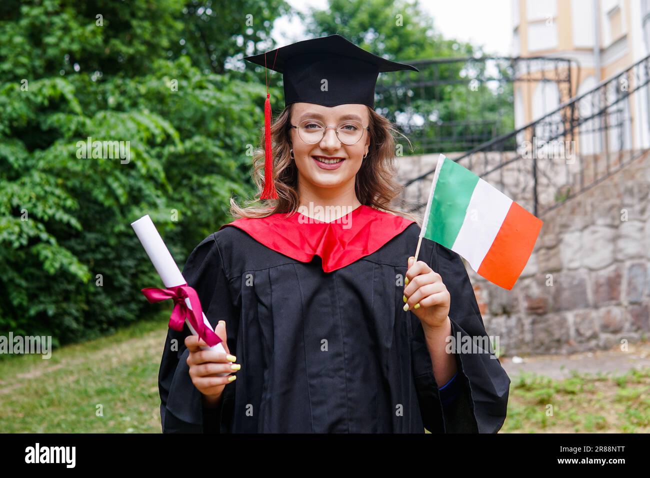 Young italian woman wearing graduation gown and hat holding flag of ...