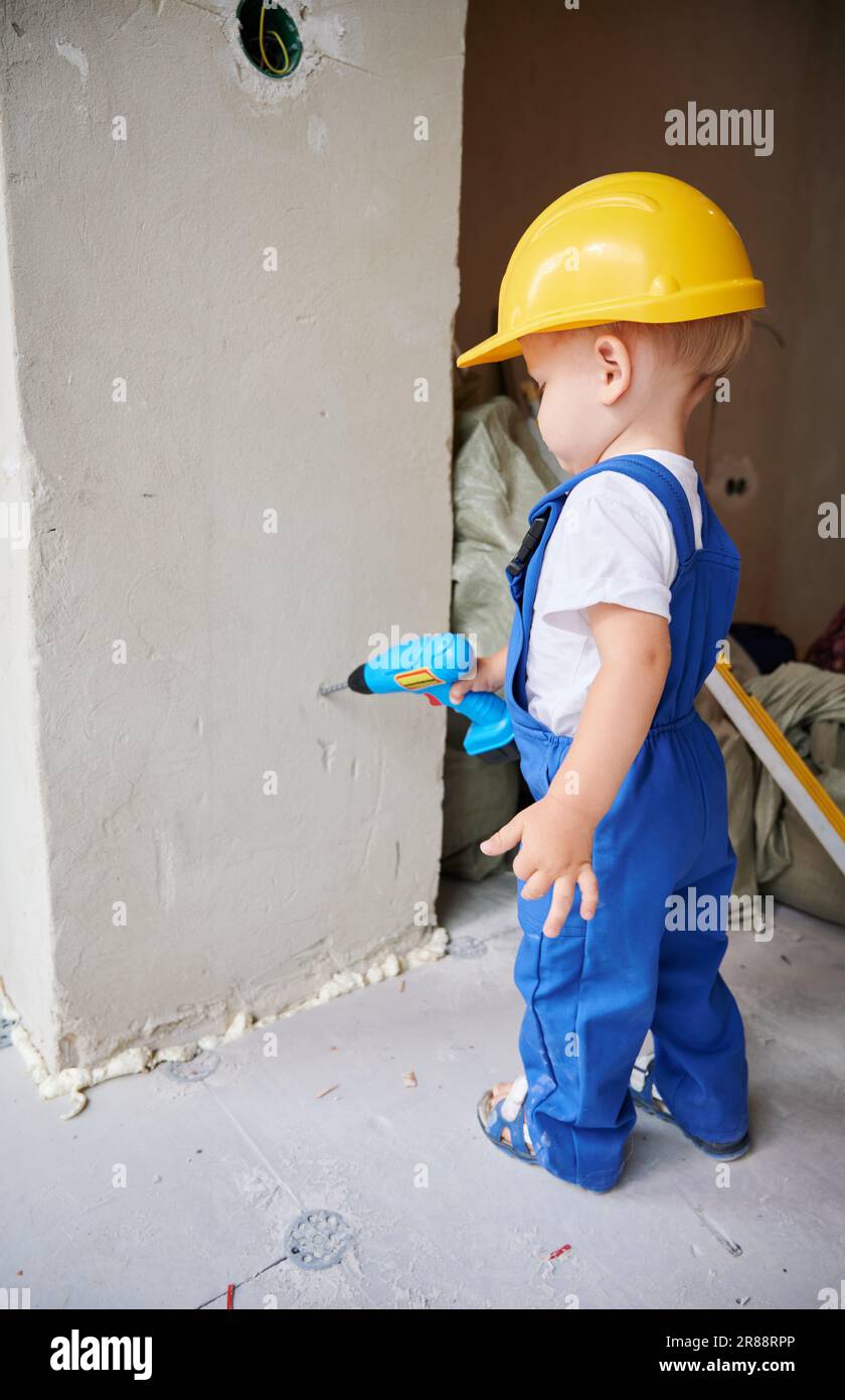 Child drilling wall with toy electric drill tool in apartment under ...